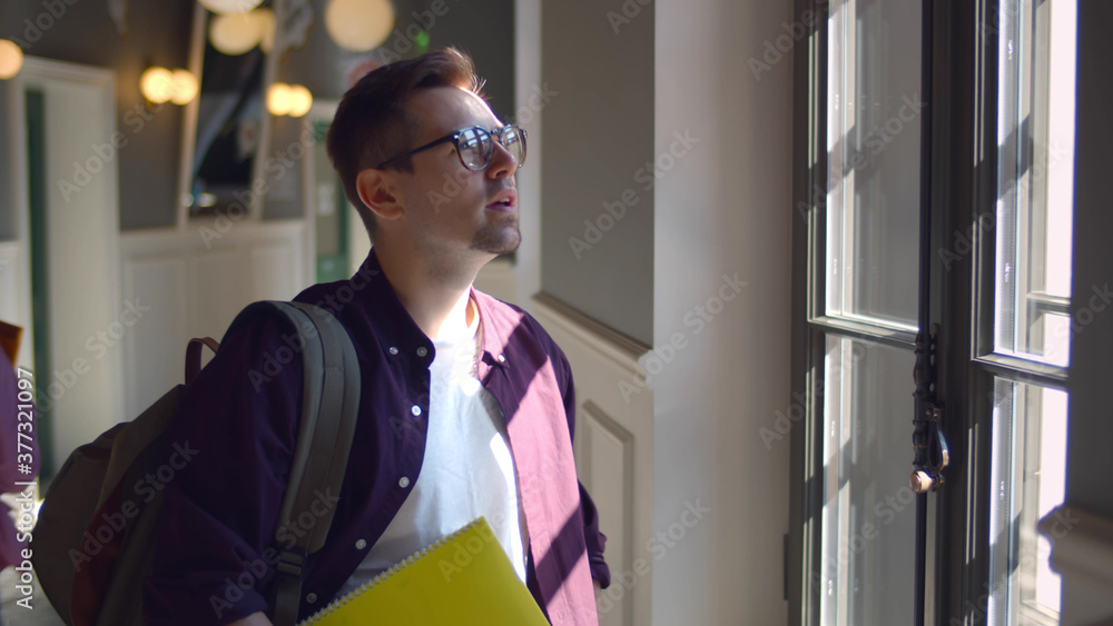 Foto Stock Young thoughtful male student looking through window ...