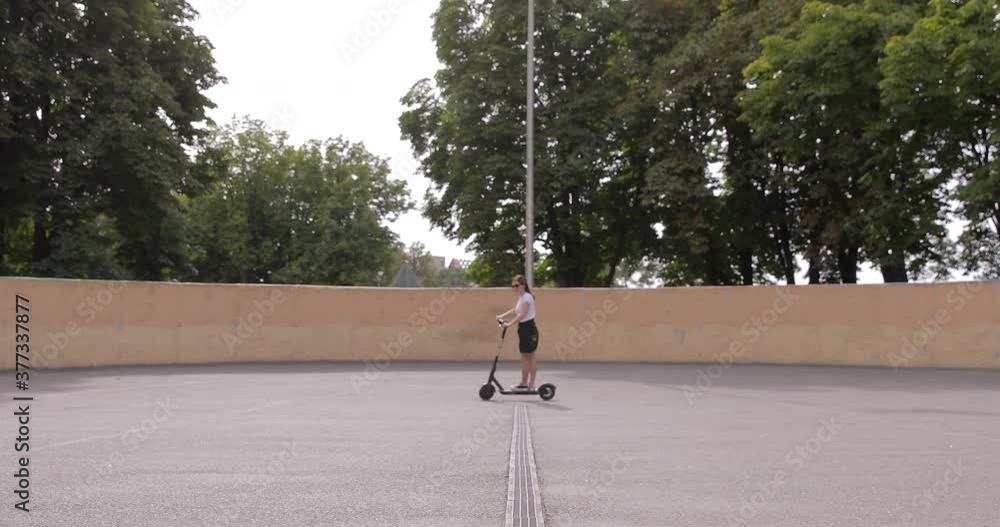 Smiling millennial woman skateboarding in the skatepark, going around a ...