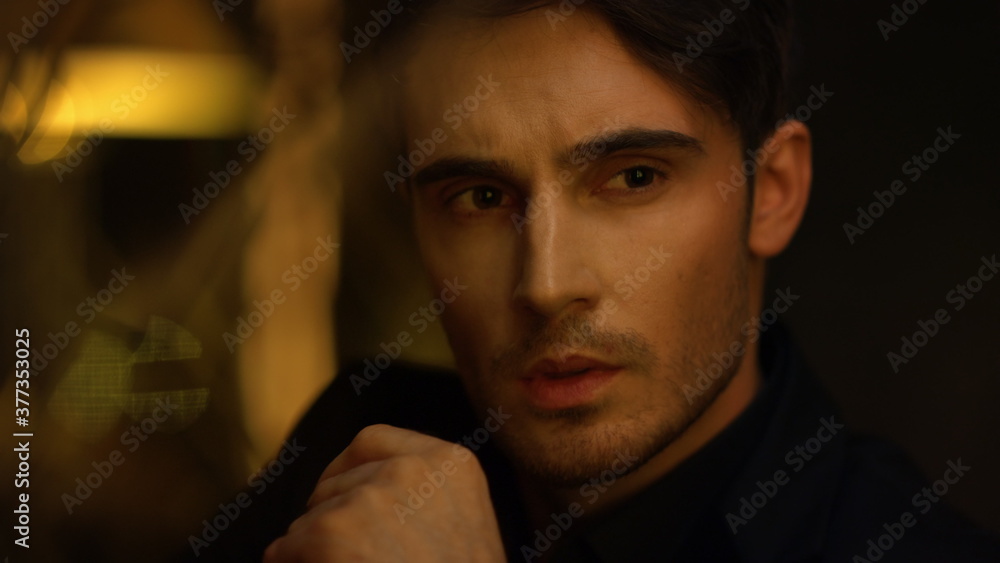 Sexy guy face viewing something in dark room. Rich man touching face ...