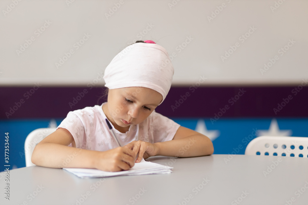 Young girl taking notes in class at school bending over his paperwork ...