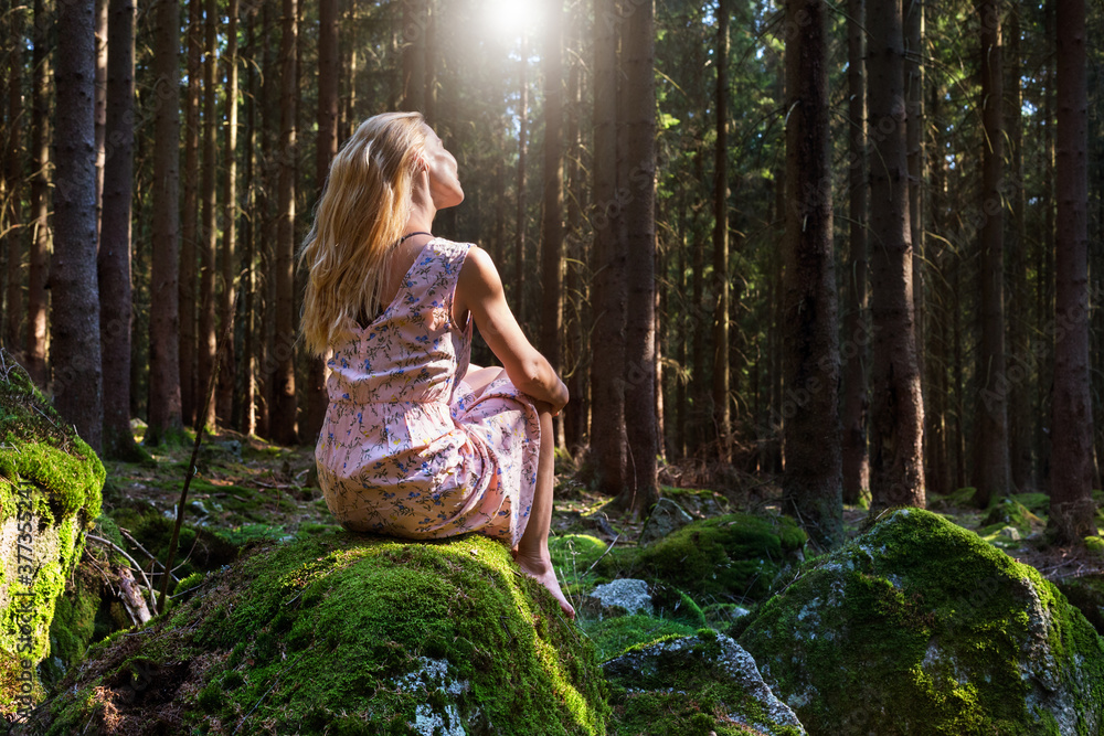 Beautiful woman sitting in green forest and enjoys beauty of nature ...