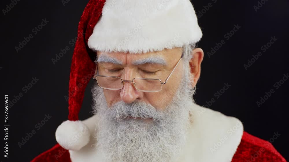 Closeup portrait of Santa Claus raising eyes at camera, adjusting ...