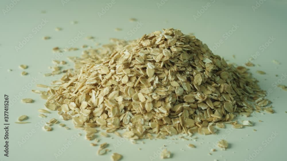 Vídeo do Stock: Grains of rolled oats or oatmeal in a heap with a slide lie on a white ...