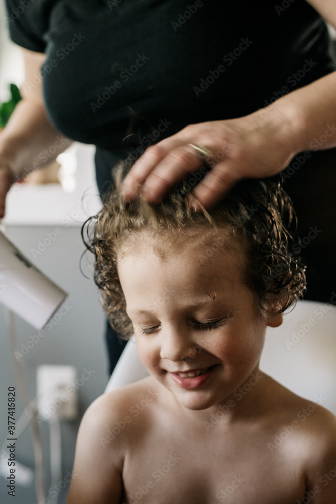 Foto de Young boy smiles while getting cut hair blown from him with a ...