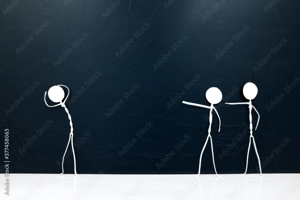 People figures pointing fingers on a scared stick man on a dark ...