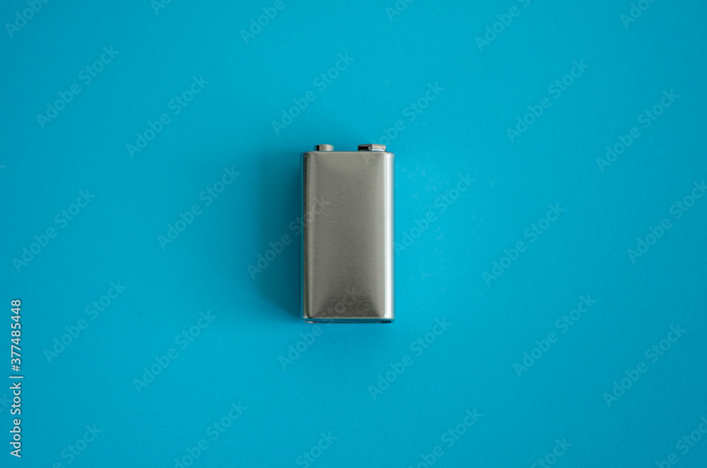 High voltage battery on a blue background. Silver Volt battery. 9V ...