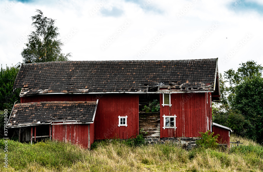 Decaying and abandoned old red barn with holes in the walls and roof ...