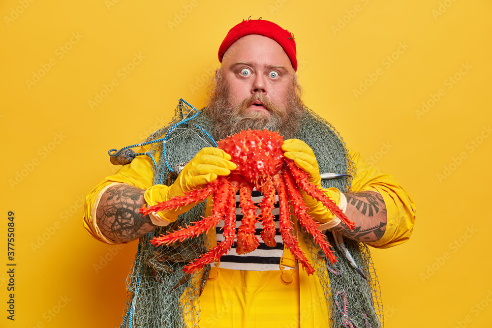 Photo of scared bearded boatswain holds big red octopus in hands ...