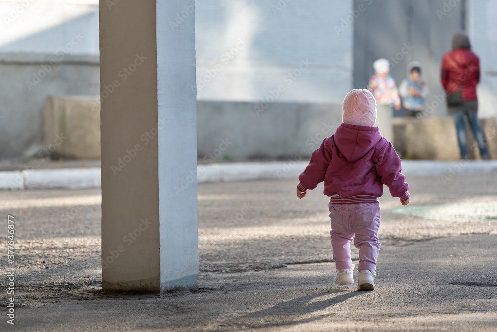 Toddler runs to the children. Little girl walking on the street. Child ...