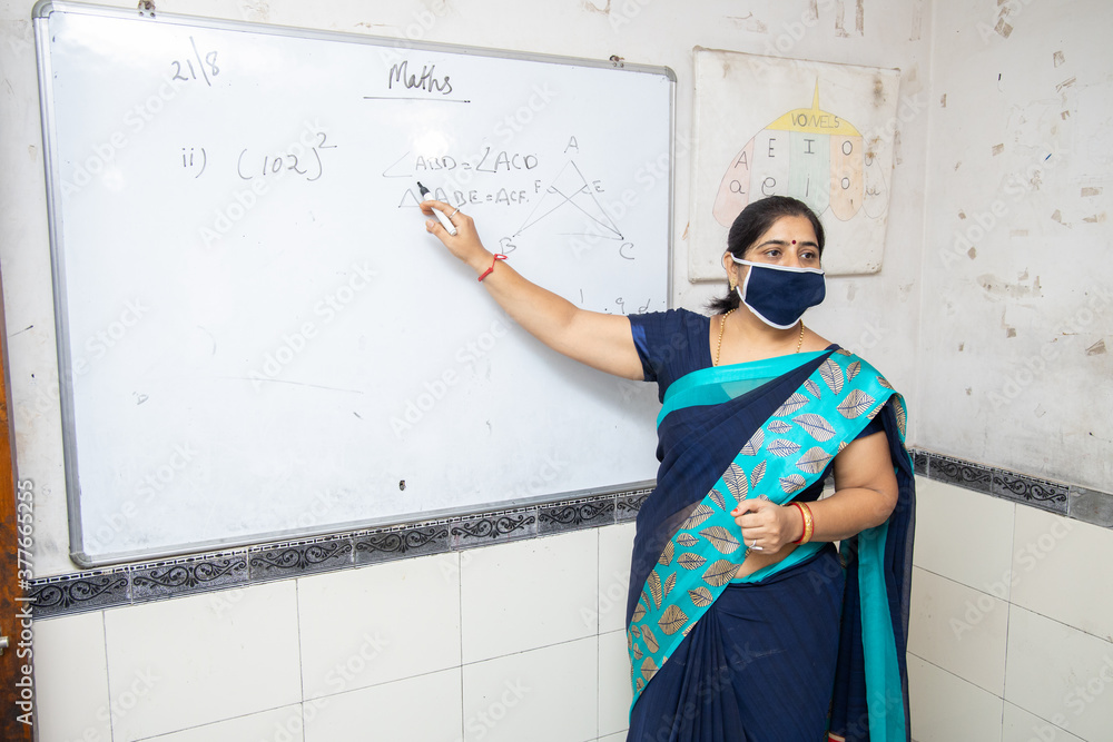 Female Teacher Wearing Mask and saree teach math on whiteboard in ...