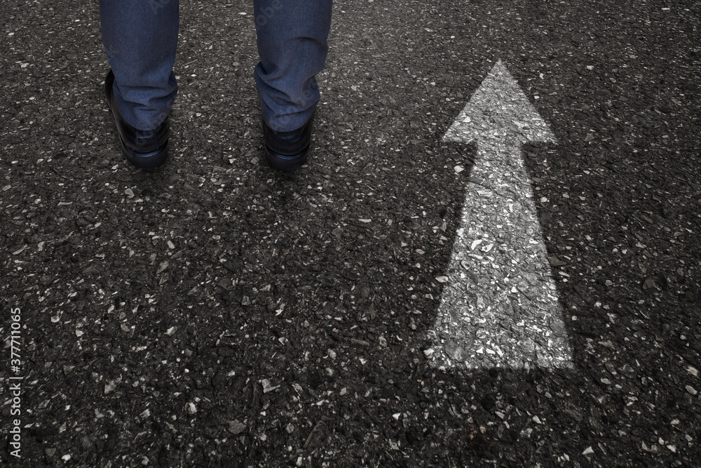 Foto de A person standing on a asphalt road with an arrow pointing ...