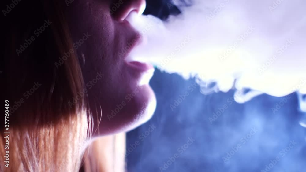 Female smoking shisha in a dark room of a nightclub. Media. Close up ...