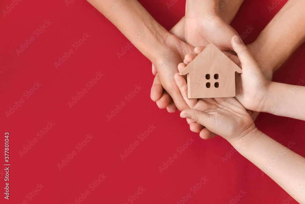 Hands of family with small house on color background Stock Photo ...