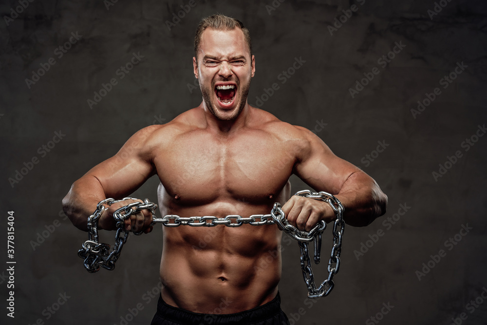 Confident bodybuilder with musculate body and with chains posing and ...