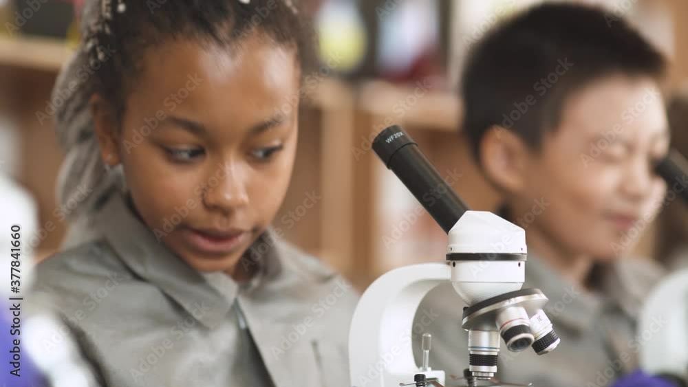 Lesson in a modern school, kids look at microscopes and communicate in ...