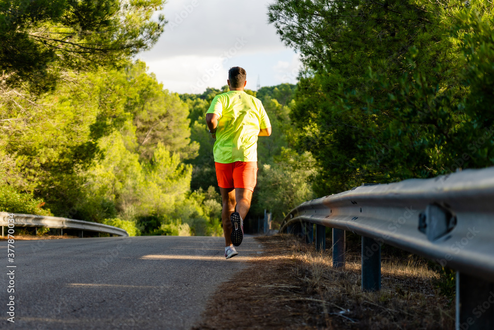 Young Spanish man with black hair and dark skin running down a path ...