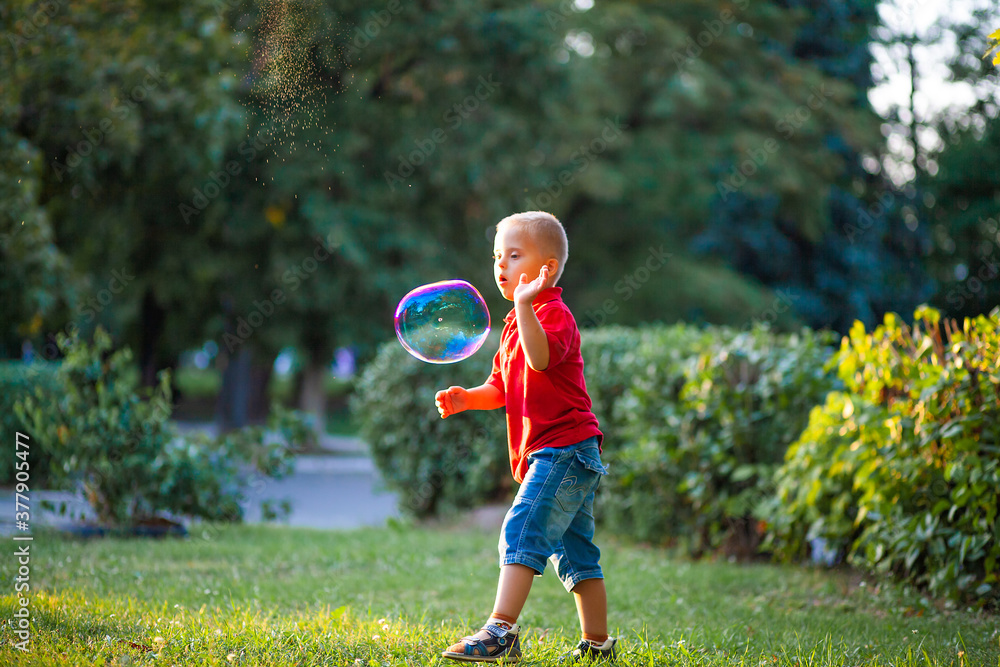 Little cute boy with Down Syndrome plays with huge soap bubbles in the ...