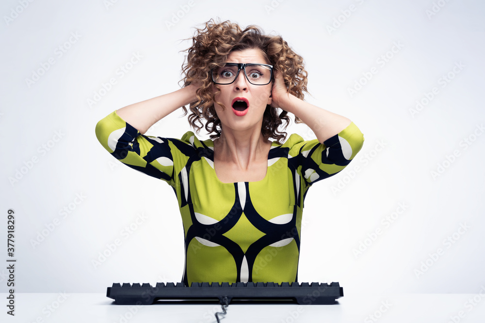 Young emotional scared woman in glasses sitting in front of a computer ...