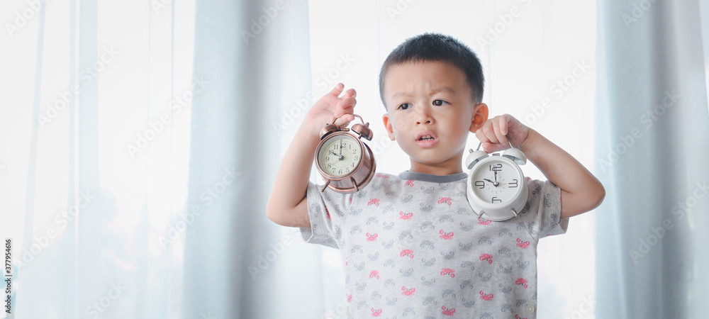 Asian cute boy holding alarm clock Along with making a curious face ...