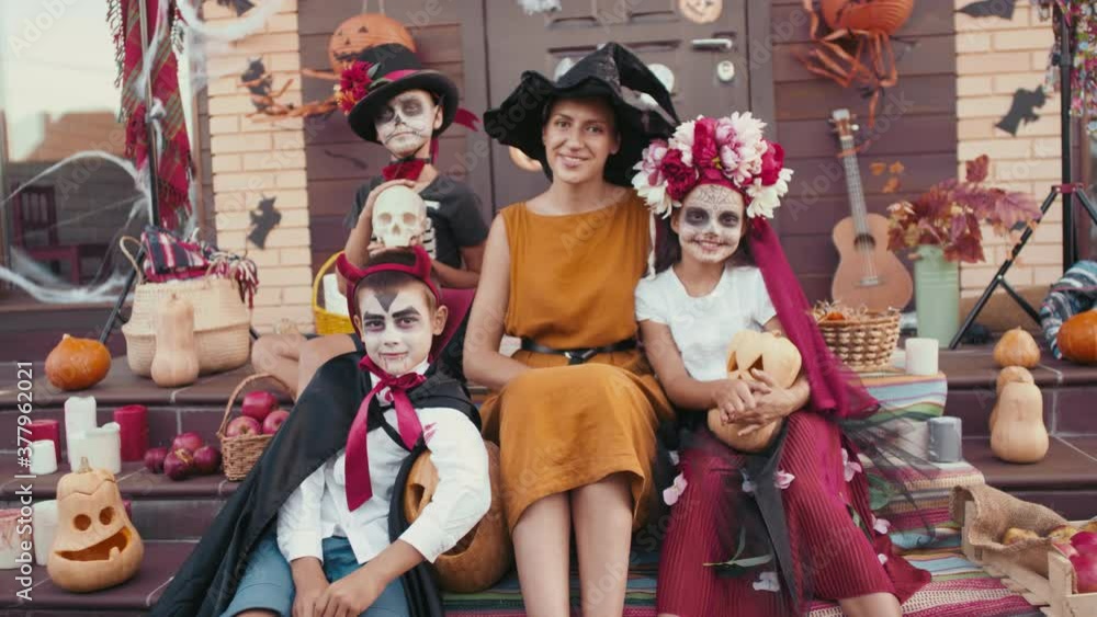 Handheld portrait shot of young woman in witch hat and three kids in ...