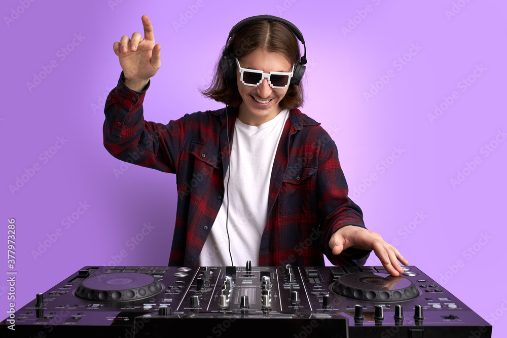 positive male DJ playing music on purple background, caucasian long ...