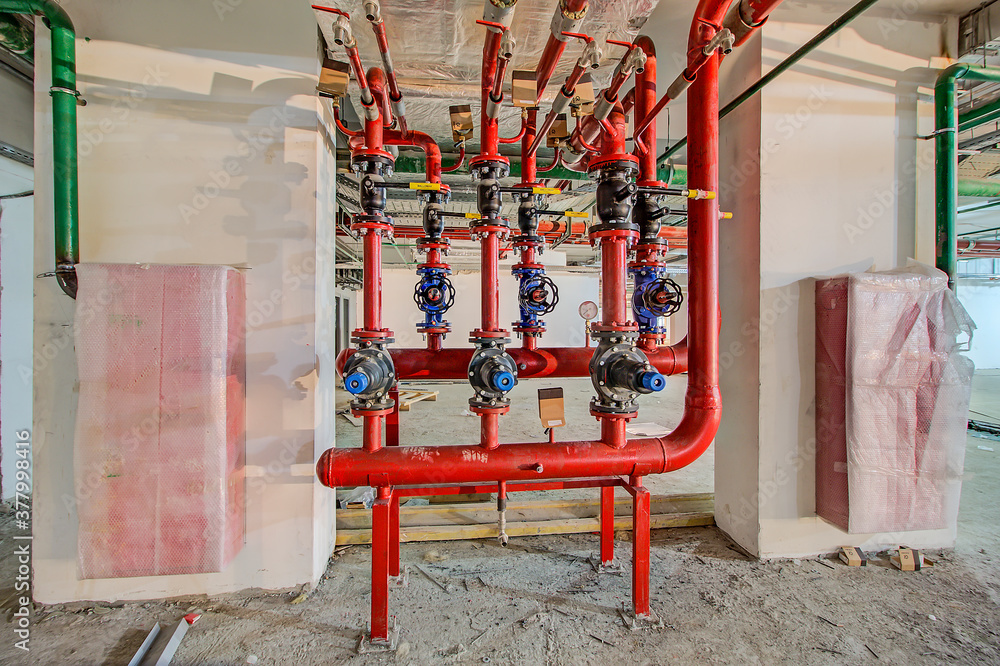 Mounting red and green piping. Installation of fittings in basement of ...