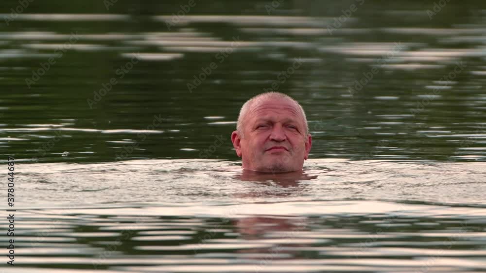 Vidéo Stock The man stuck his hairless head out of the water and swims ...