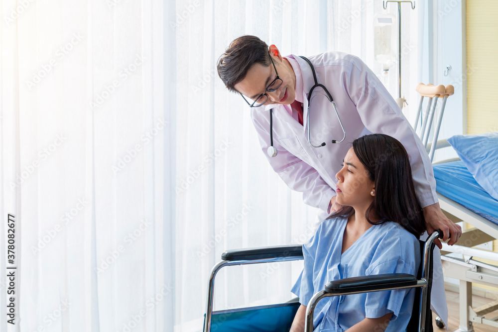 Young male doctor encouraging his female patient in hospital while ...