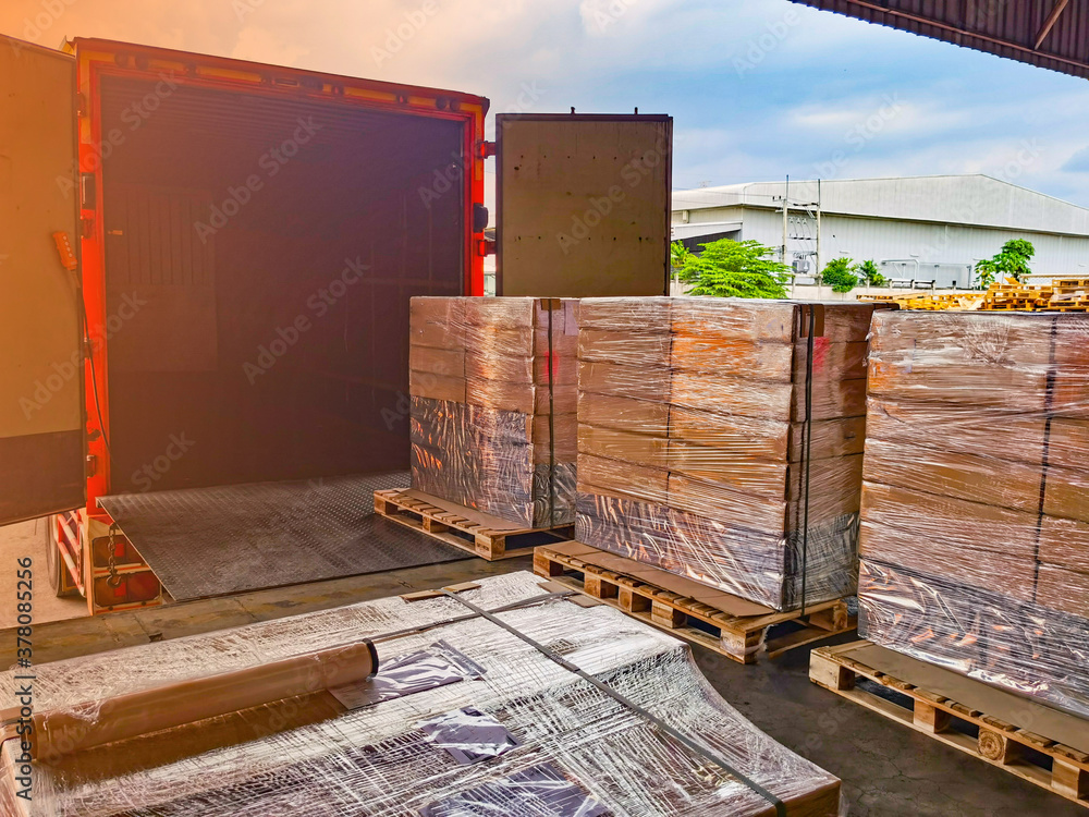 Worker driving forklift loading shipment carton boxes goods on wooden ...