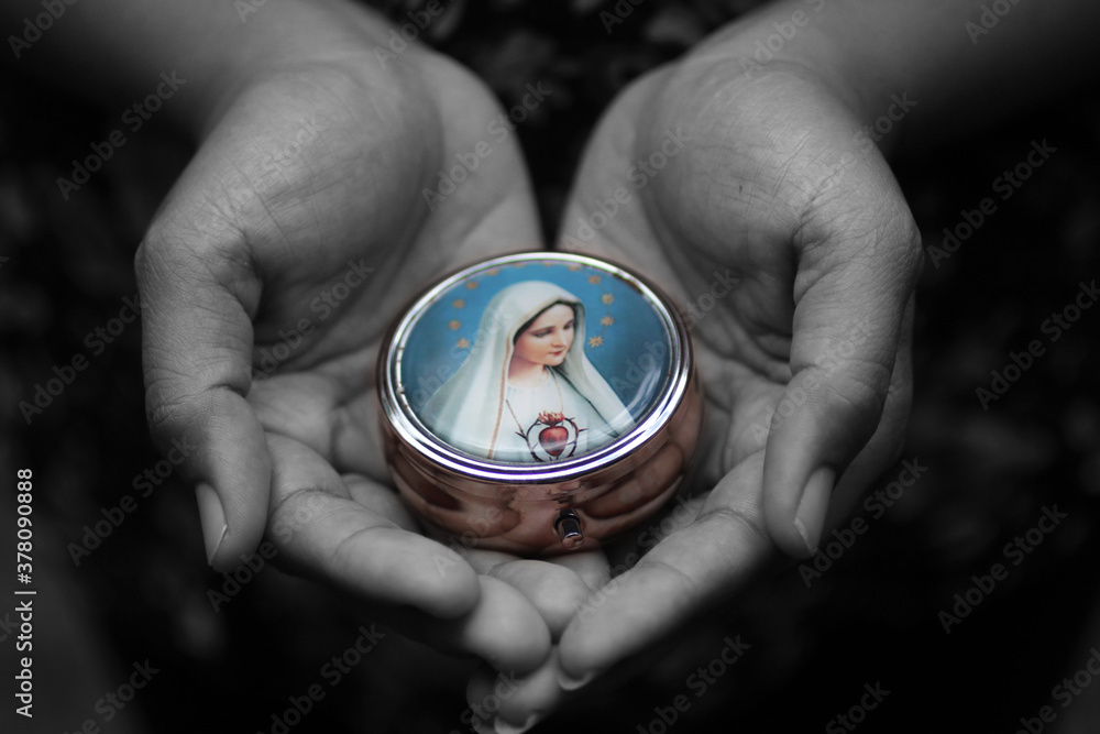 Portrait of Mother Virgin Mary on round metal rosary box in open hands ...
