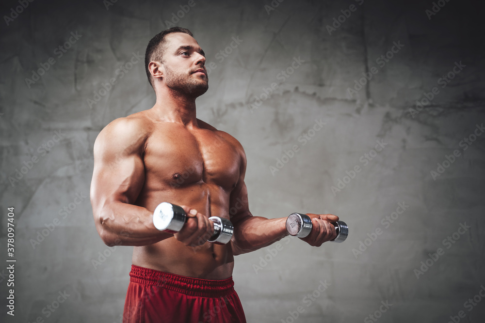 Handsome and strong guy with muscular hands lifting iron dumbells in ...