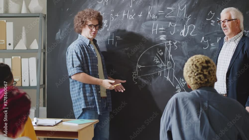 Male college student answering questions of senior professor while ...