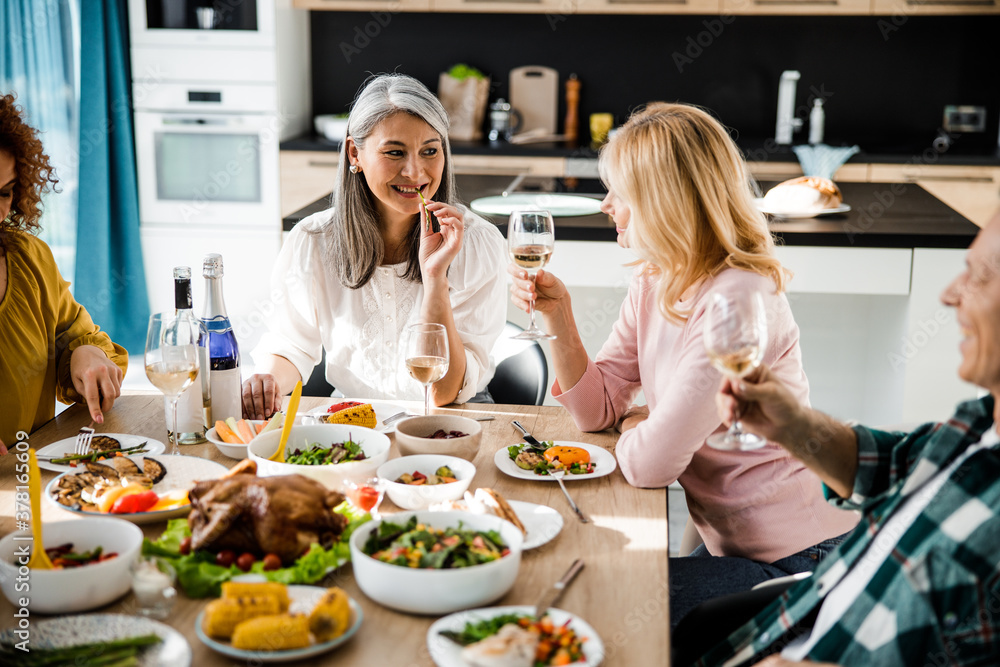 Smiling two women looking each other at the festive table in a cozy ...