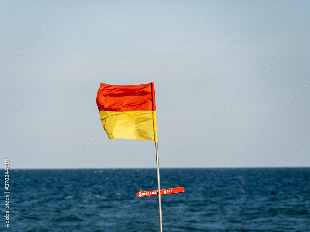 A lifeguard flag blowing in the wind to indicate the boundary of the ...