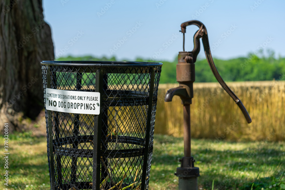 Wire trash can in cemetery with sign stating cemetery decorations only ...