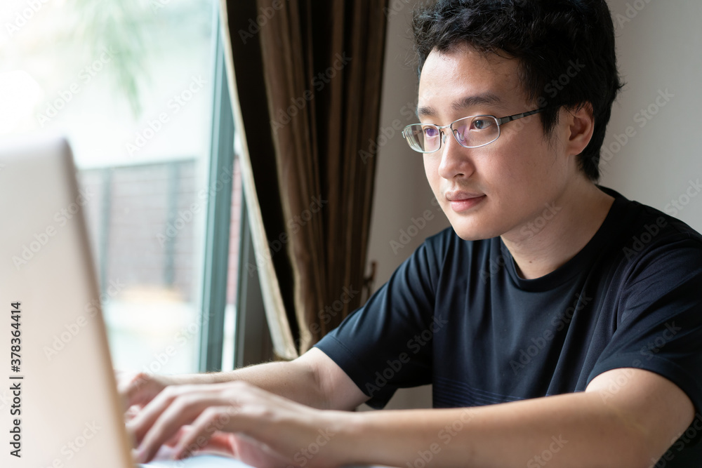 Asian young man working and checking an e-mail by using personal laptop ...