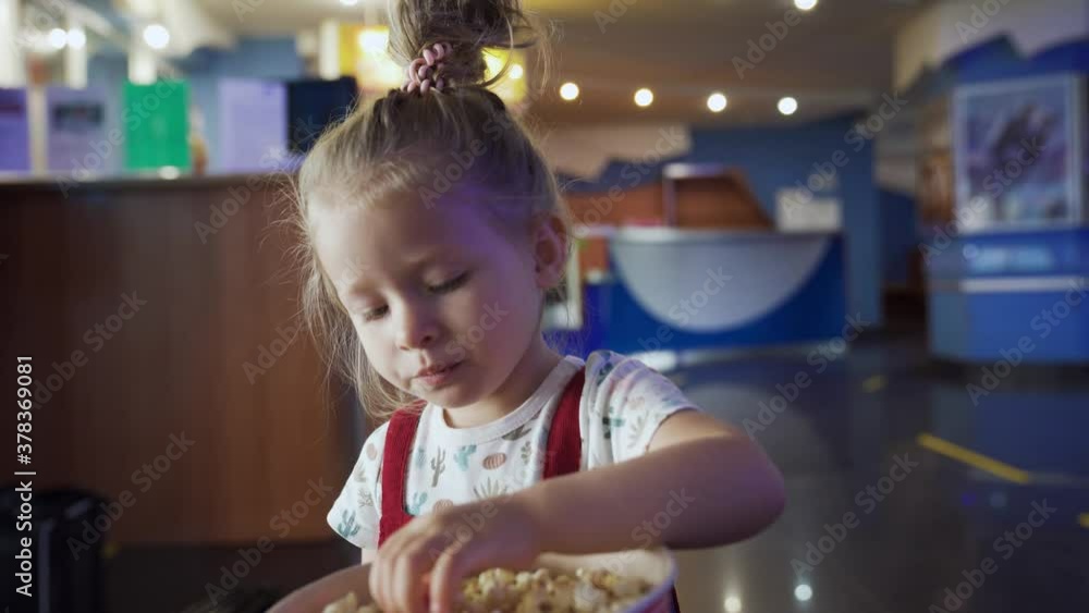 Little girl eating popcorn. Media. Cute girl chewing sweet popcorn at ...