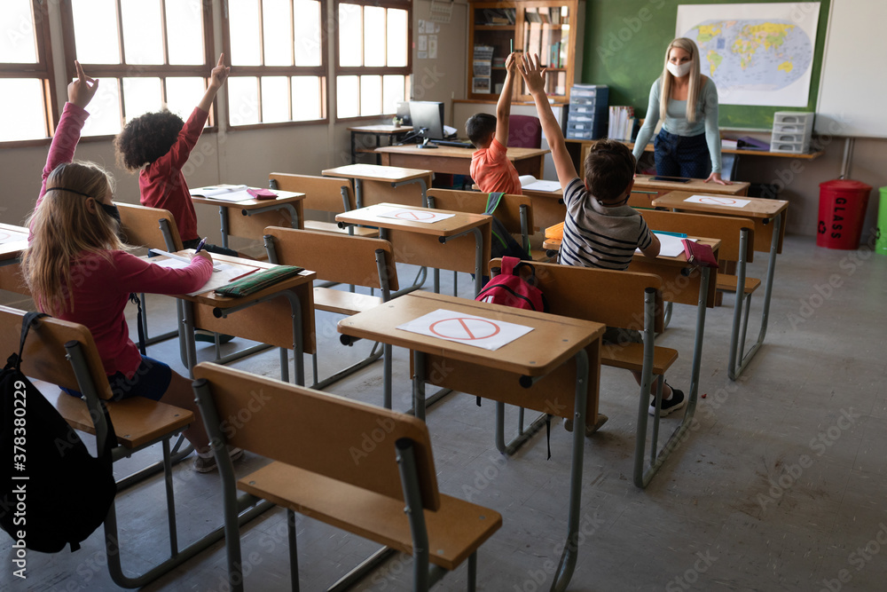 Group of kids wearing face masks raising their hands in the class Stock ...