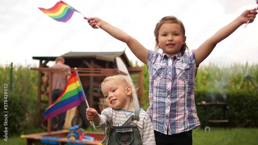 Children, boy and girl, play in the yard with rainbow LGBT flags. LGBT ...