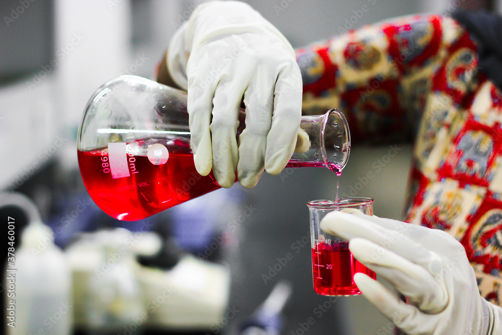 Foto de pouring a red liquid from a glass conical flask to a glass ...