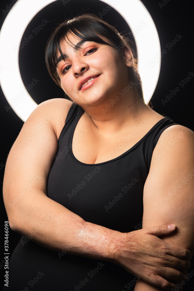 Hispanic woman smiling on black background and a ring of light behind ...