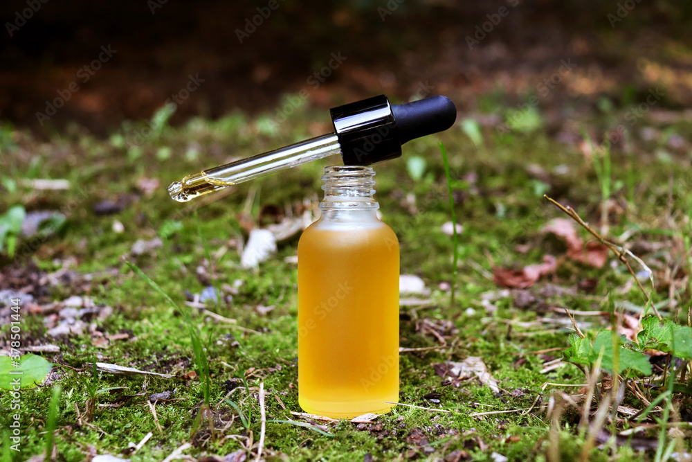 Mockup of dropper oil bottle, wild nature background. Biophilic eco ...