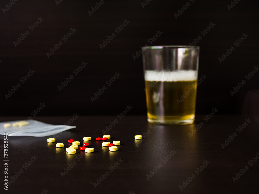 Ecstasy Pills with blur image of beer in glass on black background ...