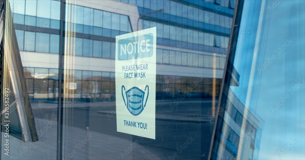 Face mask required poster hanging on a window of an office building ...