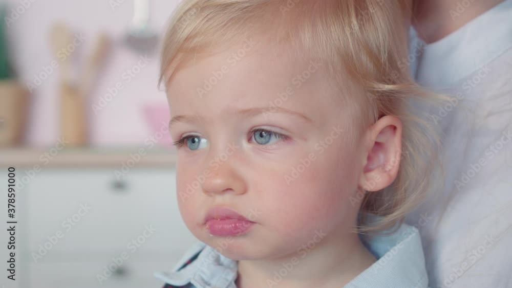 Close-up face of charming little blond boy with blue eyes chewing ...