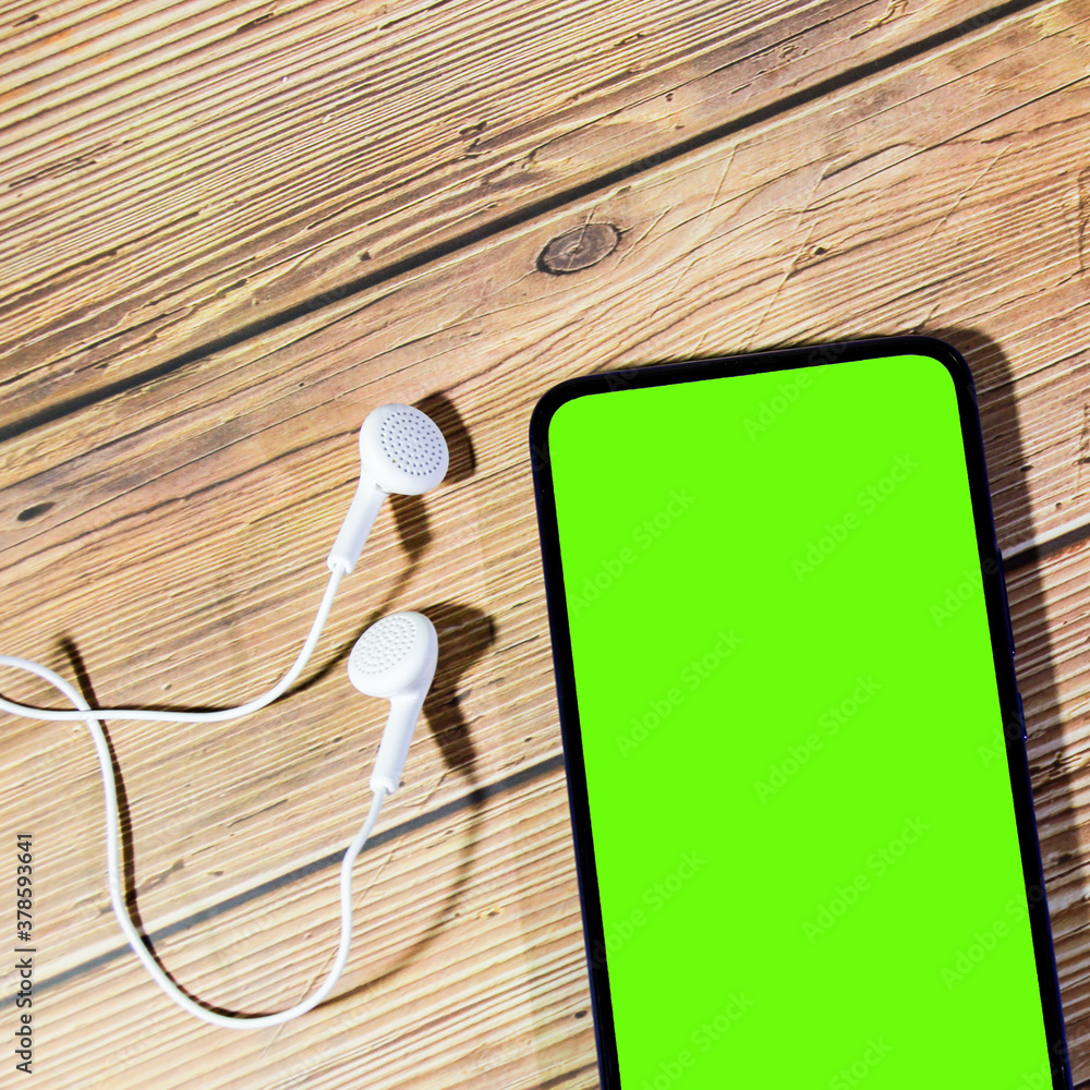 Mobile phone green screen for copy space and headphones for listening ...