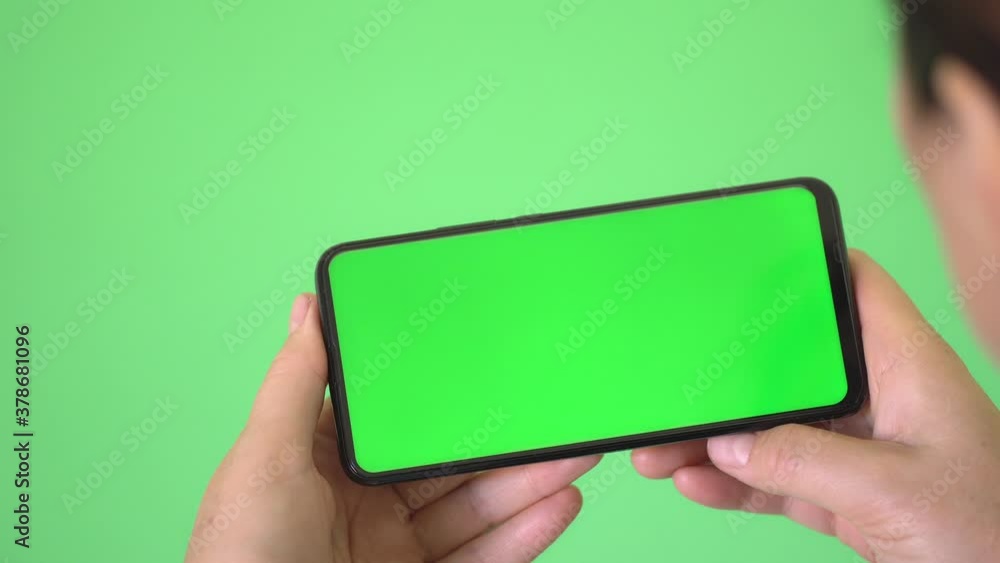 woman's hand holding a mobile telephone with a vertical green screen in tram chroma key ...
