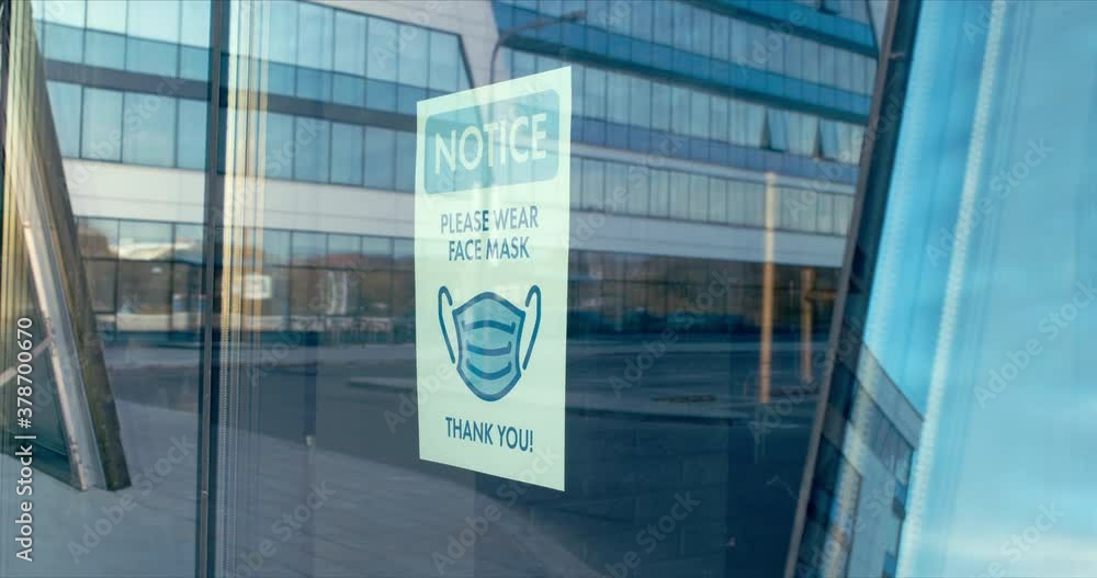 Face mask required informational poster hanging on a window of an ...