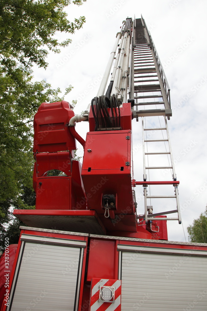 Modern red fire truck back view with tall extendable fire ladder close ...