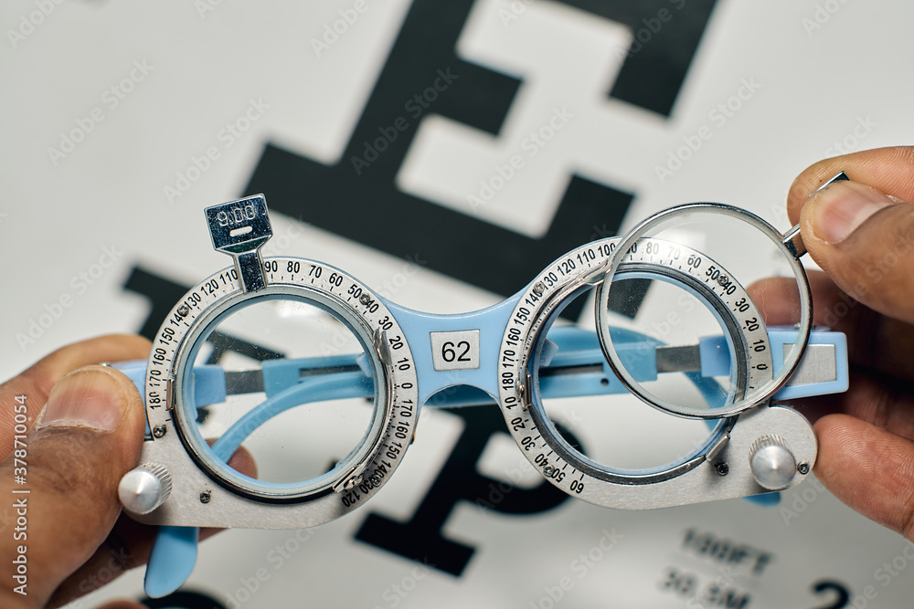 Optician holding trial frame and set of corrective lens with snellen ...